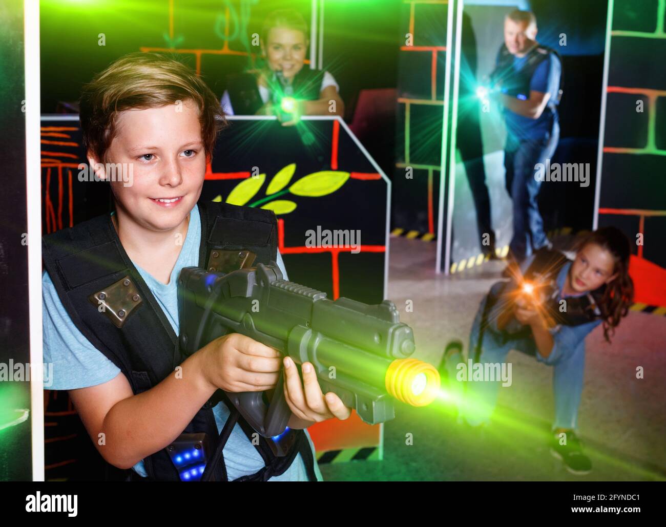 Excited cheerful positive smiling boy aiming laser gun at other players ...