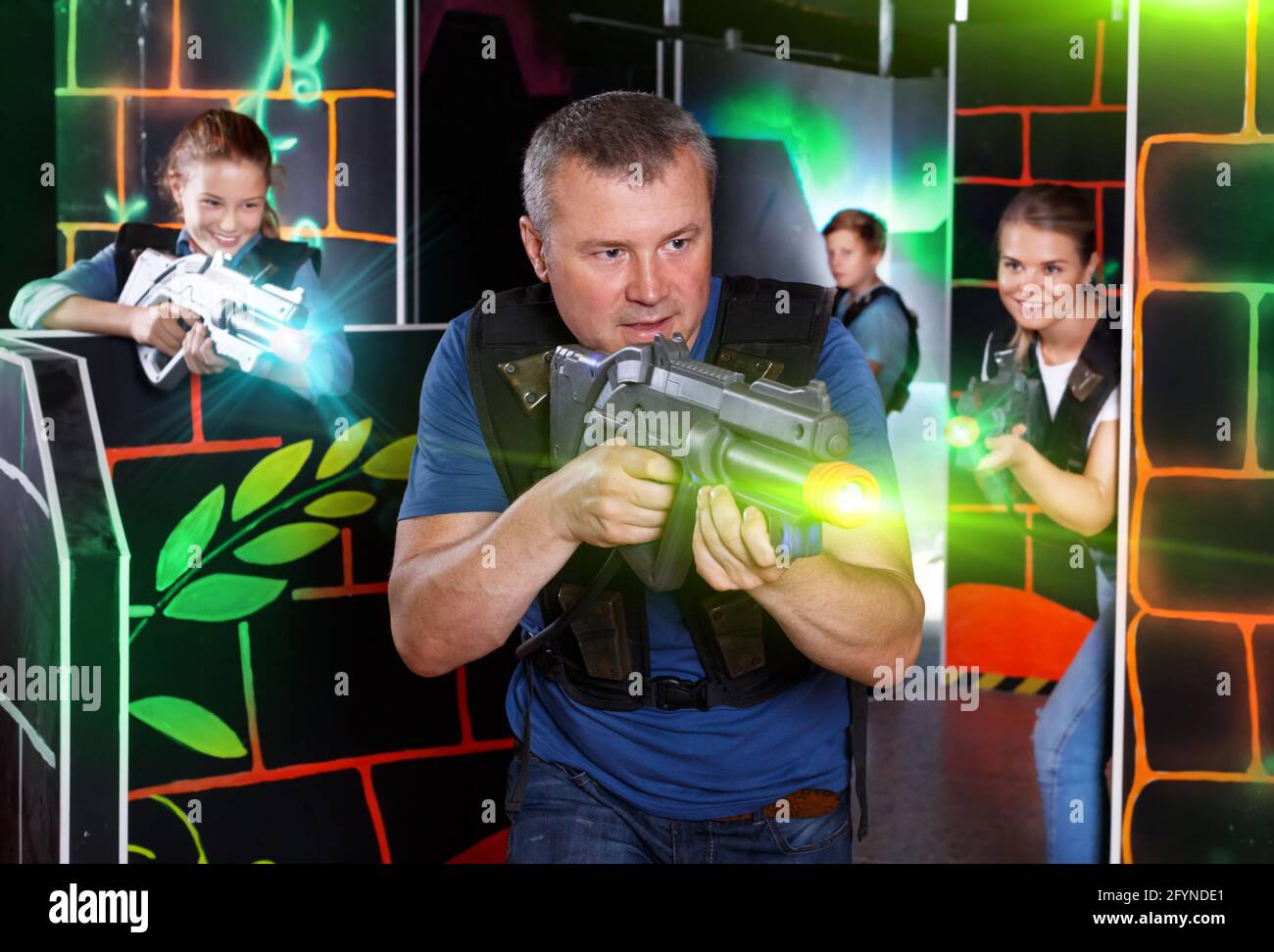 Emotional man with laser pistol playing laser tag with his family in a ...
