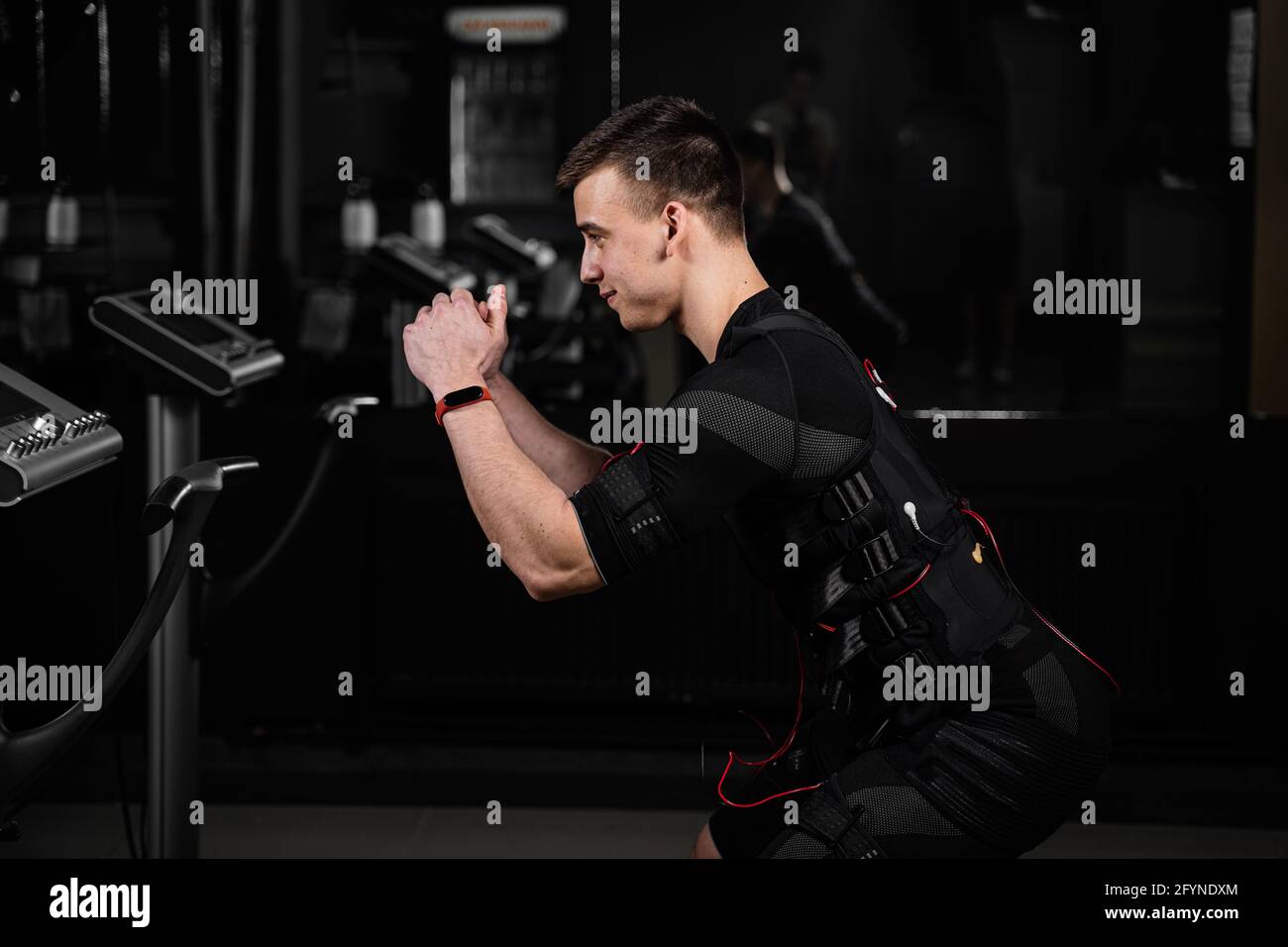 Making physical exercises using EMS suit in gym. Sport training in ...