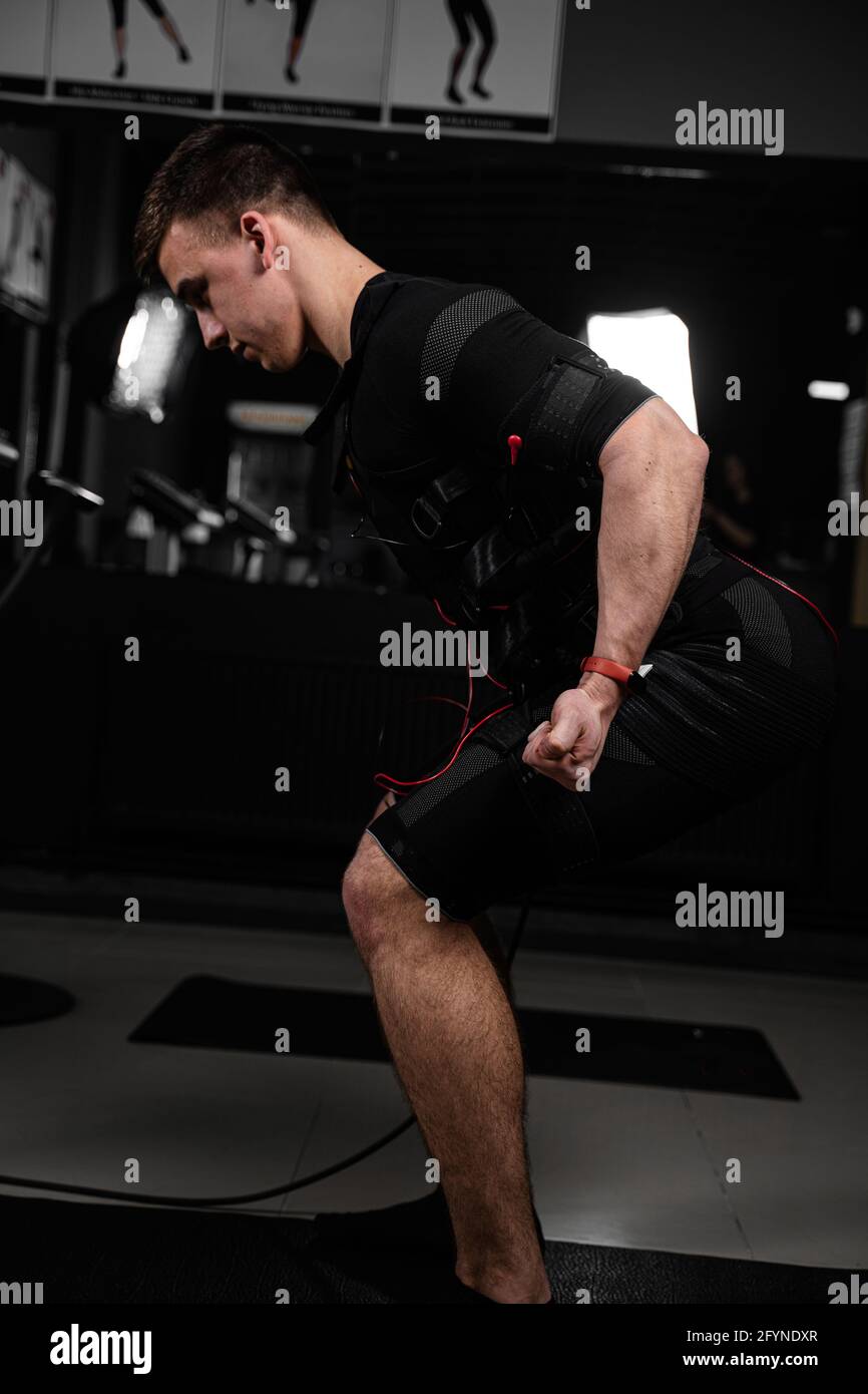 Making physical exercises using EMS suit in gym. Sport training in ...
