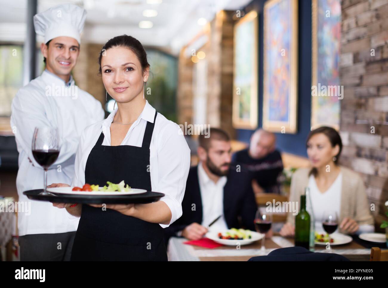 Portrait of a smiling waitress with professional chef in restaurant ...