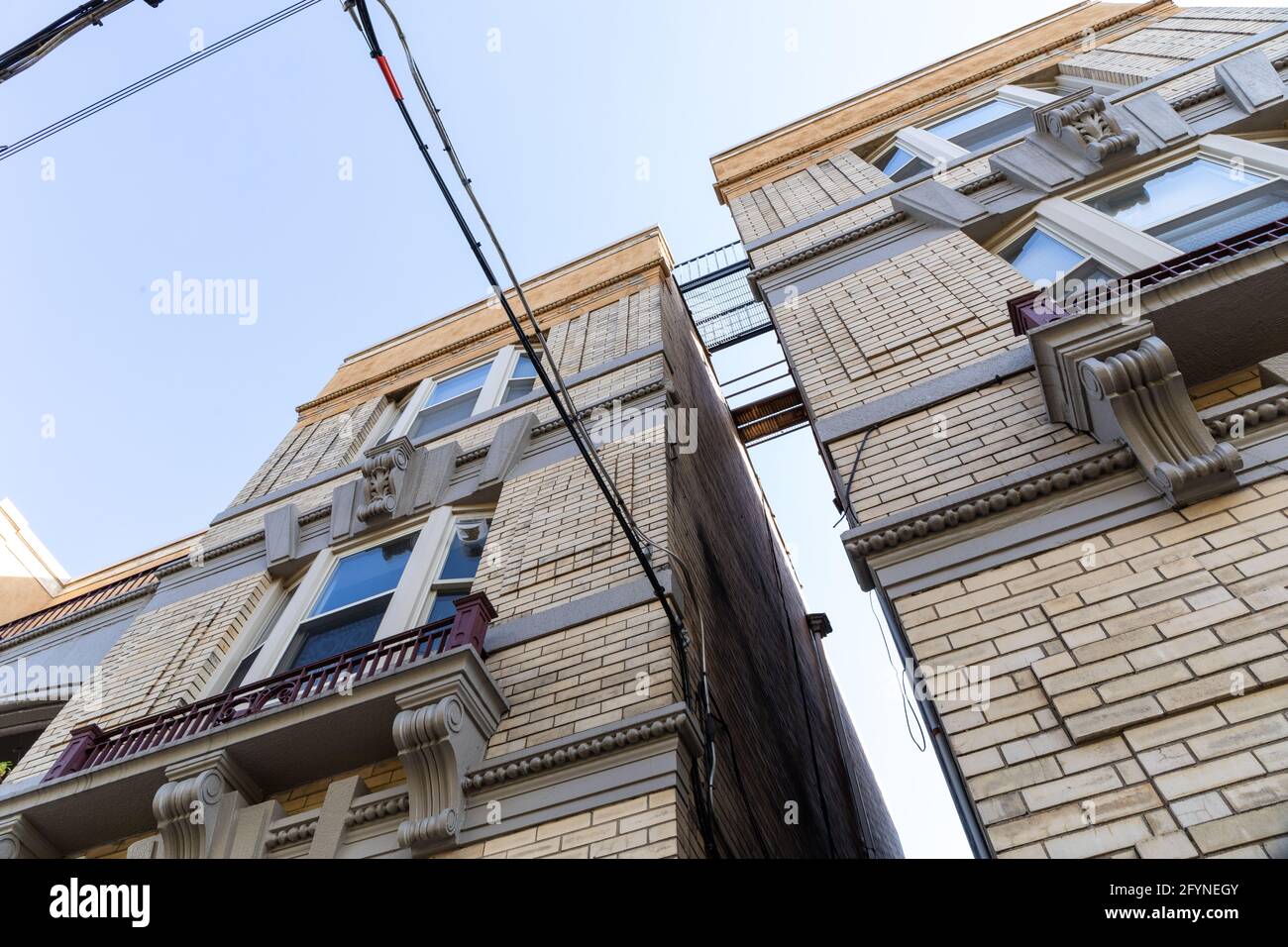 Two tan brick apartment buildings with rooftop walkways between them ...