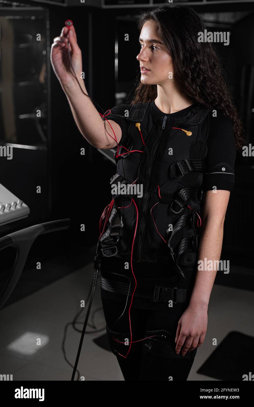 Girl with electronic contactor of EMS suit in gym. Sport training in ...