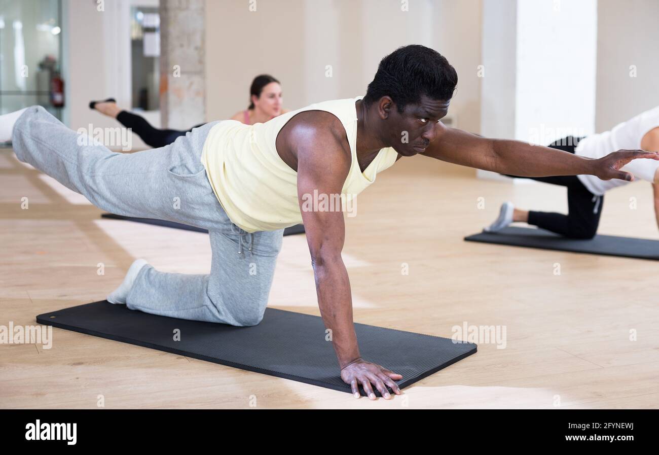 Portrait of focused African American man performing set of pilates ...
