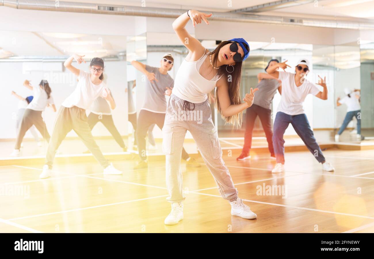 Happy smiling teenagers practicing vigorous hip hop movements in dance ...