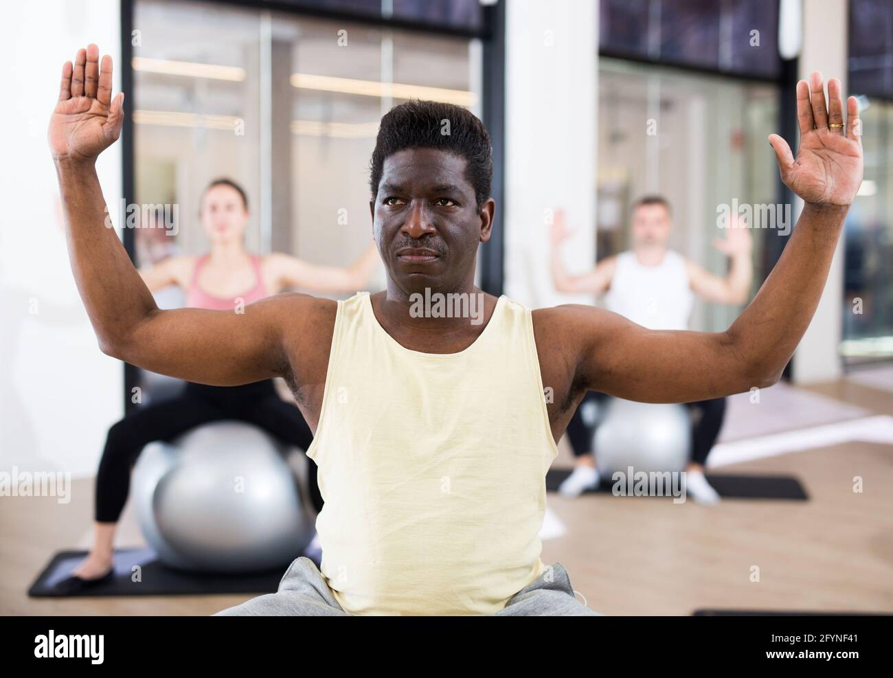 Confident young adult man doing exercises with pilates ball during ...