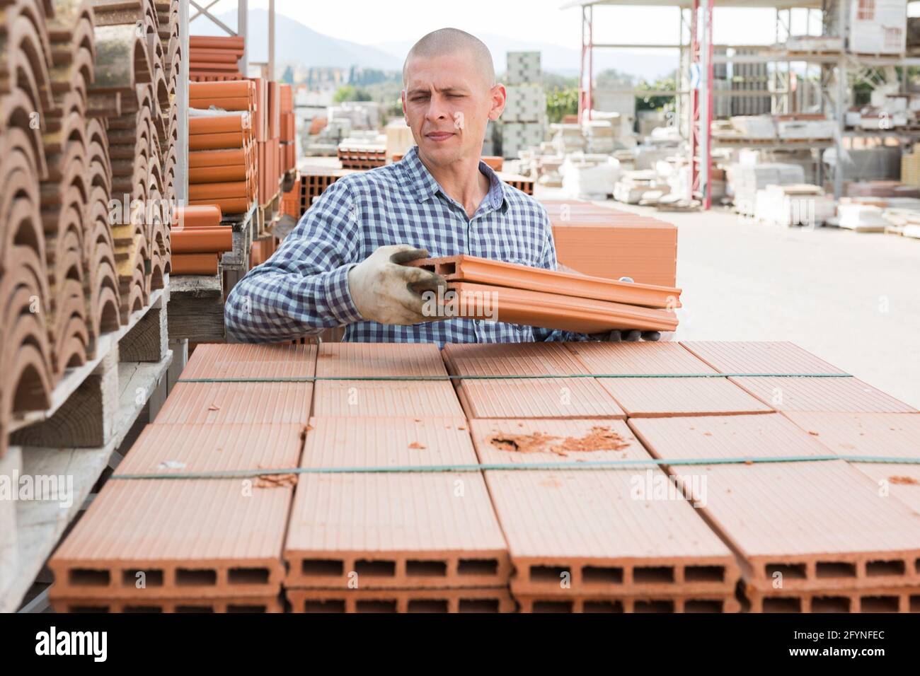Worker stacking bricks in warehouse of building materials Stock Photo ...