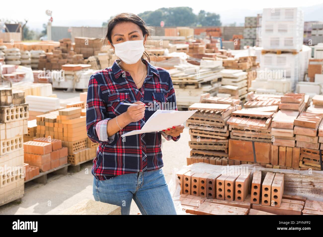 Hispanic woman supervisor in protective face mask controlling quantity ...