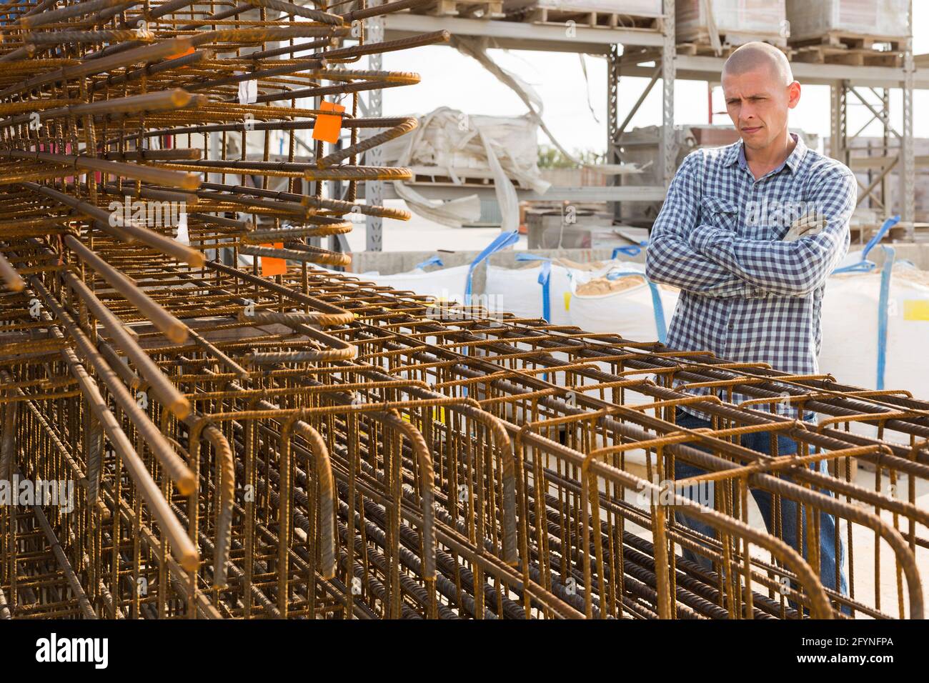 Young man worker with reinforcing steel bars during work in warehouse ...
