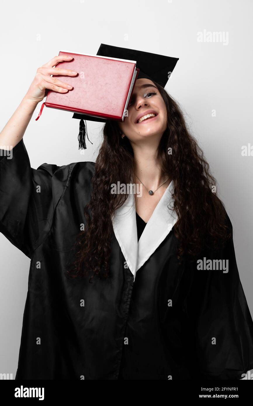 Student with book in graduation robe and cap ready to finish college ...