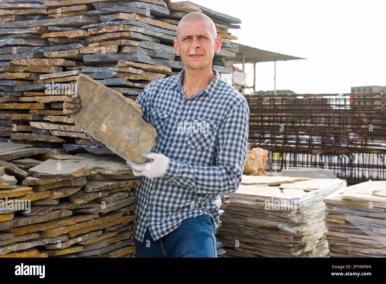 Young man salesperson checking quality of natural stone tiles at ...