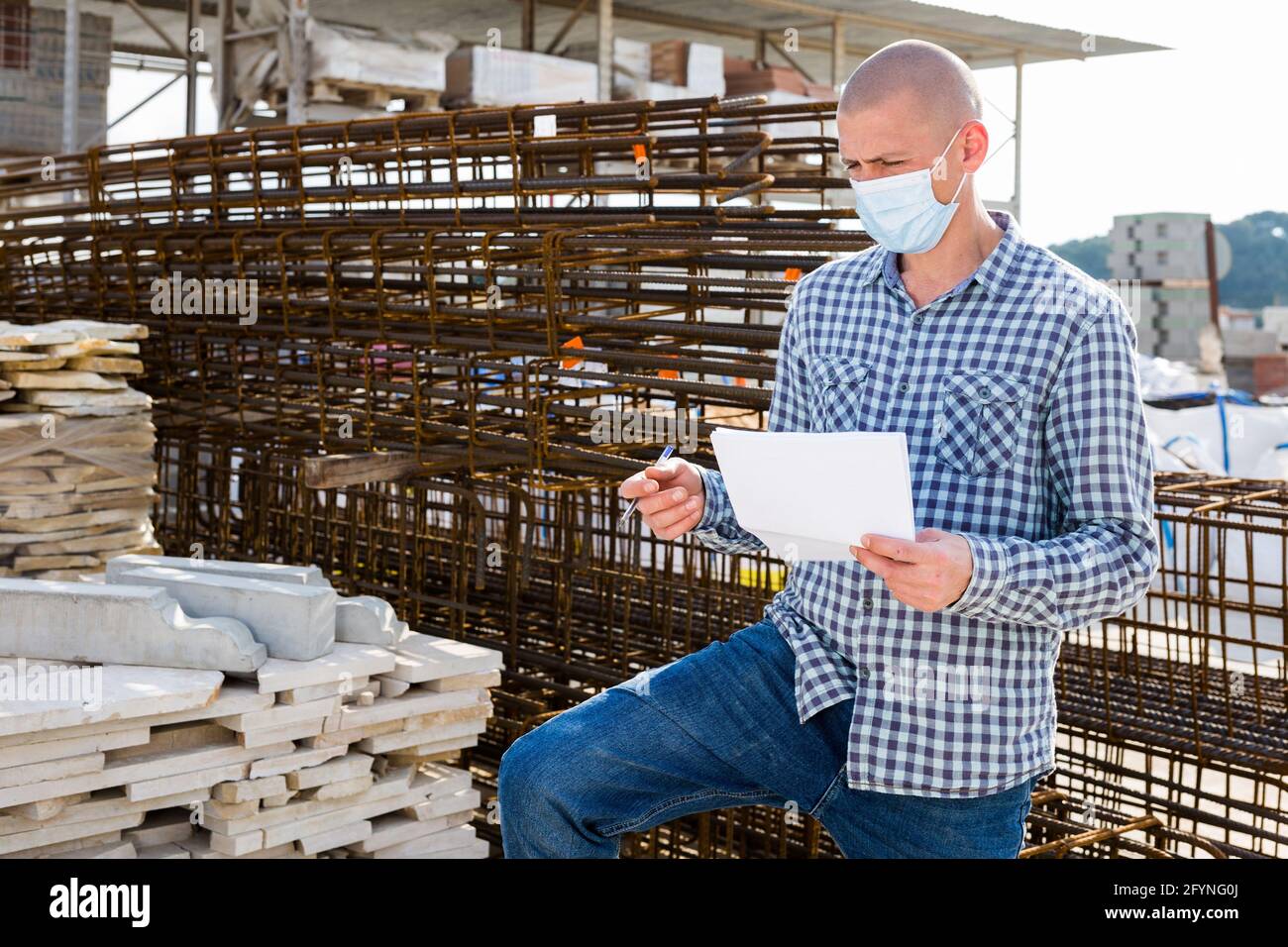 Male worker in face mask with checklist collecting order at hardware ...