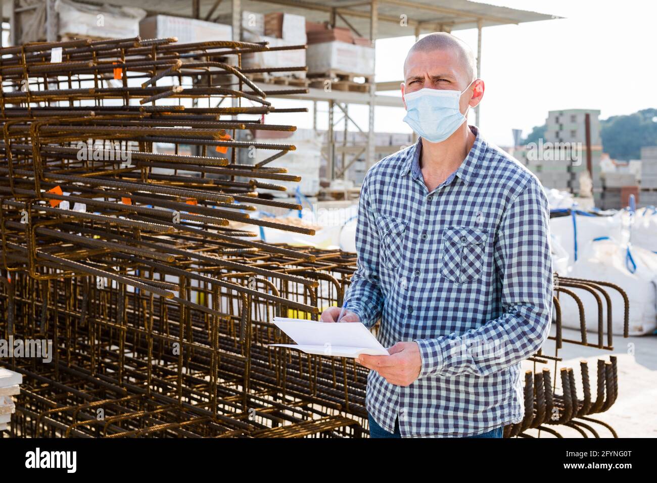 Male worker in face mask with checklist collecting order at hardware ...