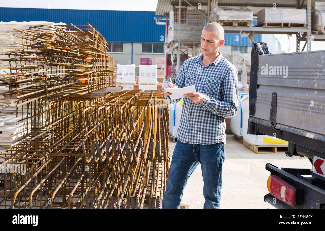 Construction shop worker prepares metal rebar for loading onto a truck ...