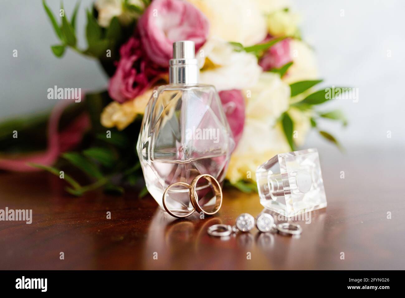 Wedding rings with perfume and a wedding bouquet on the nightstand ...