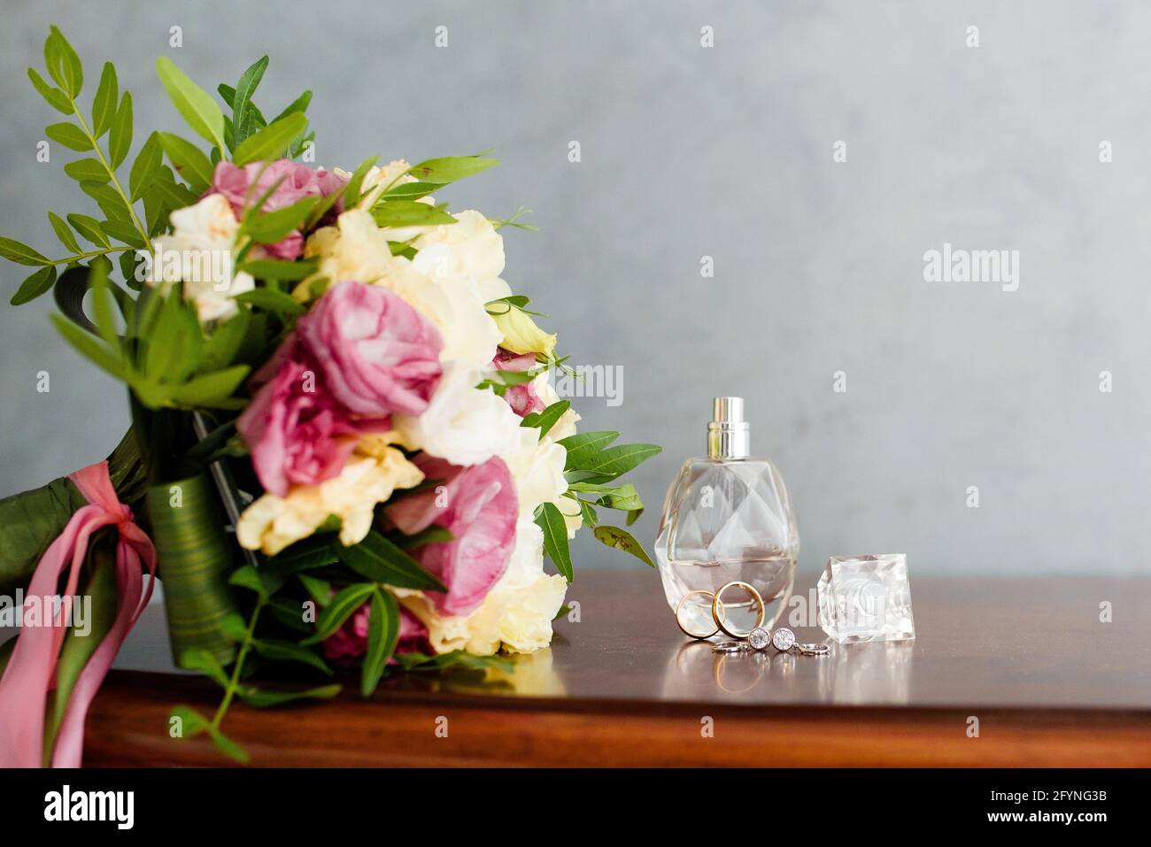 Wedding rings with perfume and a wedding bouquet on the nightstand ...