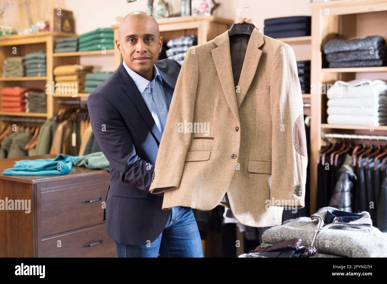 Portrait of confident salesman demonstrating suit jacket in apparel ...