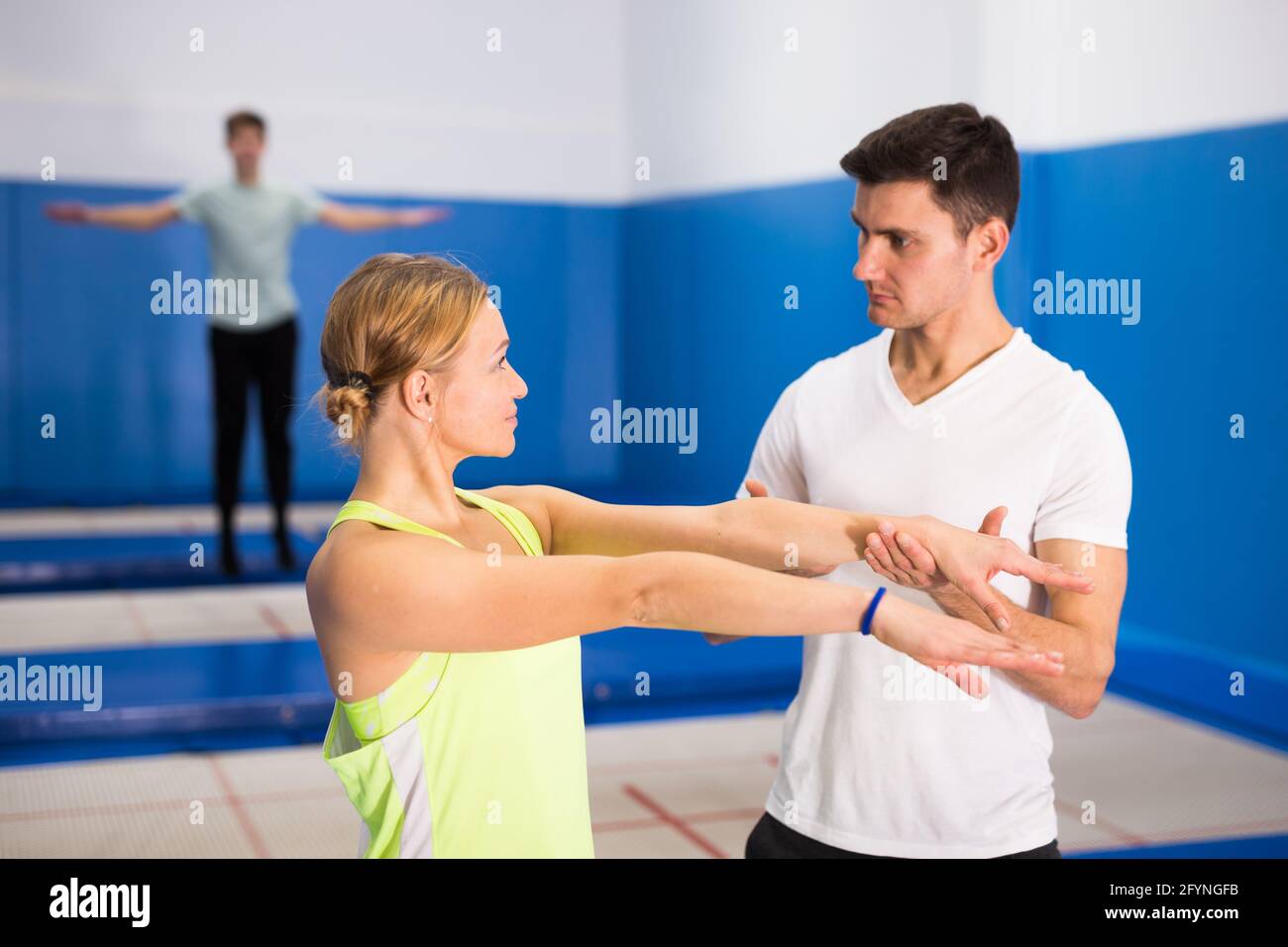 Portrait of man coach showing young woman jumping movements during ...