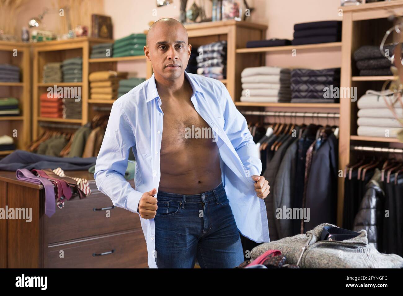 Portrait of young adult man dressing new shirt in clothing store Stock ...