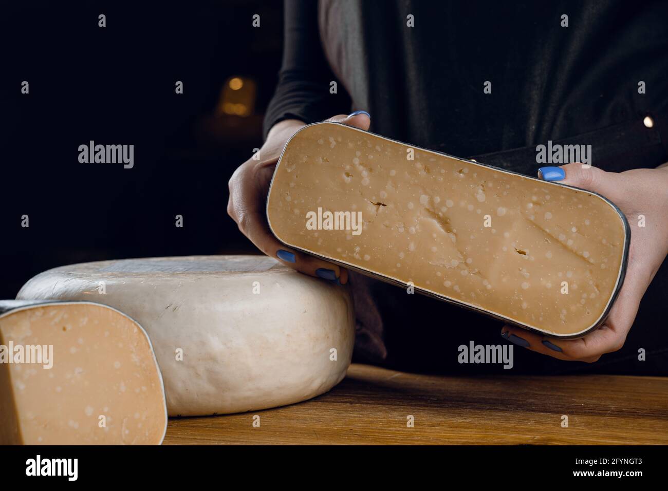 Holding goat cheese wheel and big pieces of it. Mix of cheeses from ...