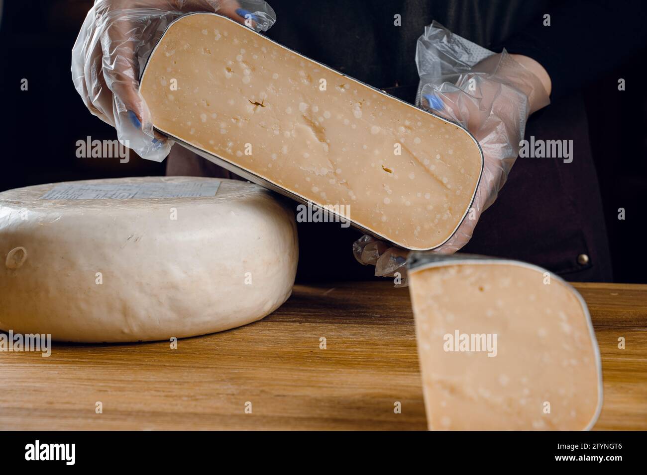 Holding goat cheese wheel and big pieces of it. Mix of cheeses from ...