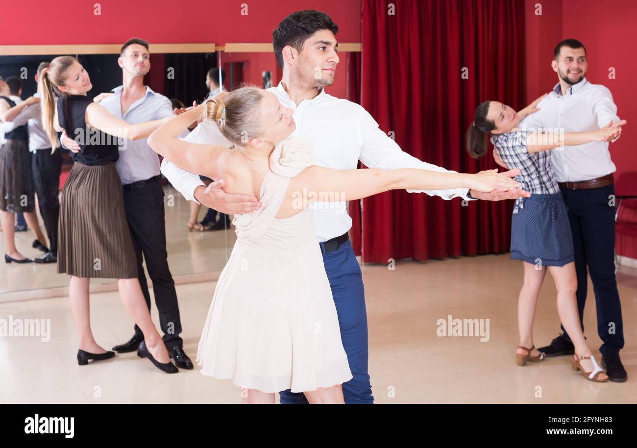 Young positive people dancing together slow ballroom dances in pairs ...