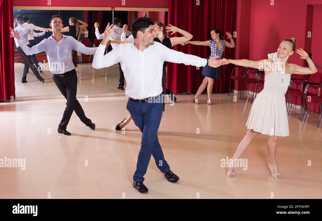 Adult dancing couples enjoying active boogie-woogie in modern studio ...