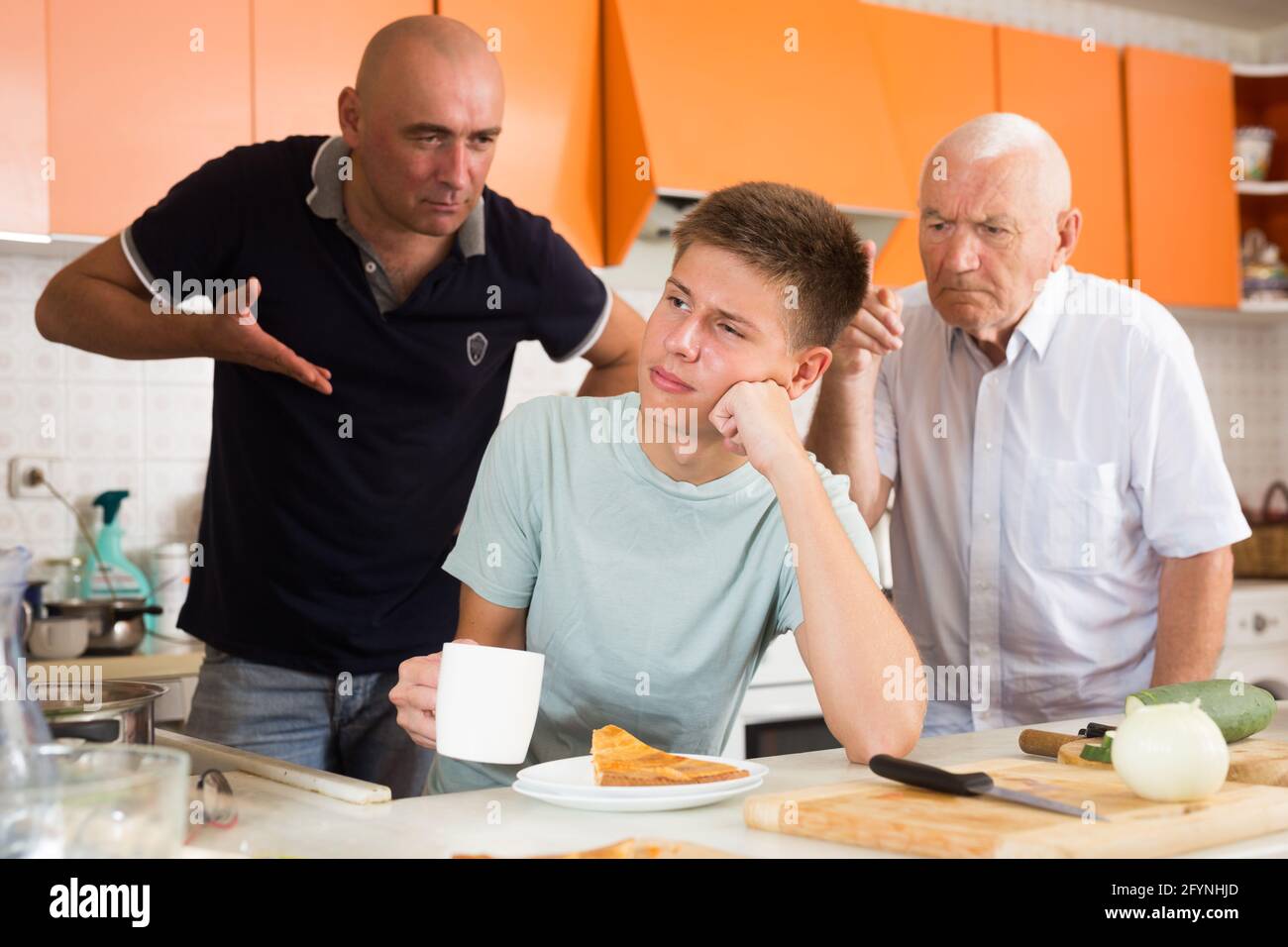 Annoyed father and grandfather scolding bored teenager at home kitchen ...