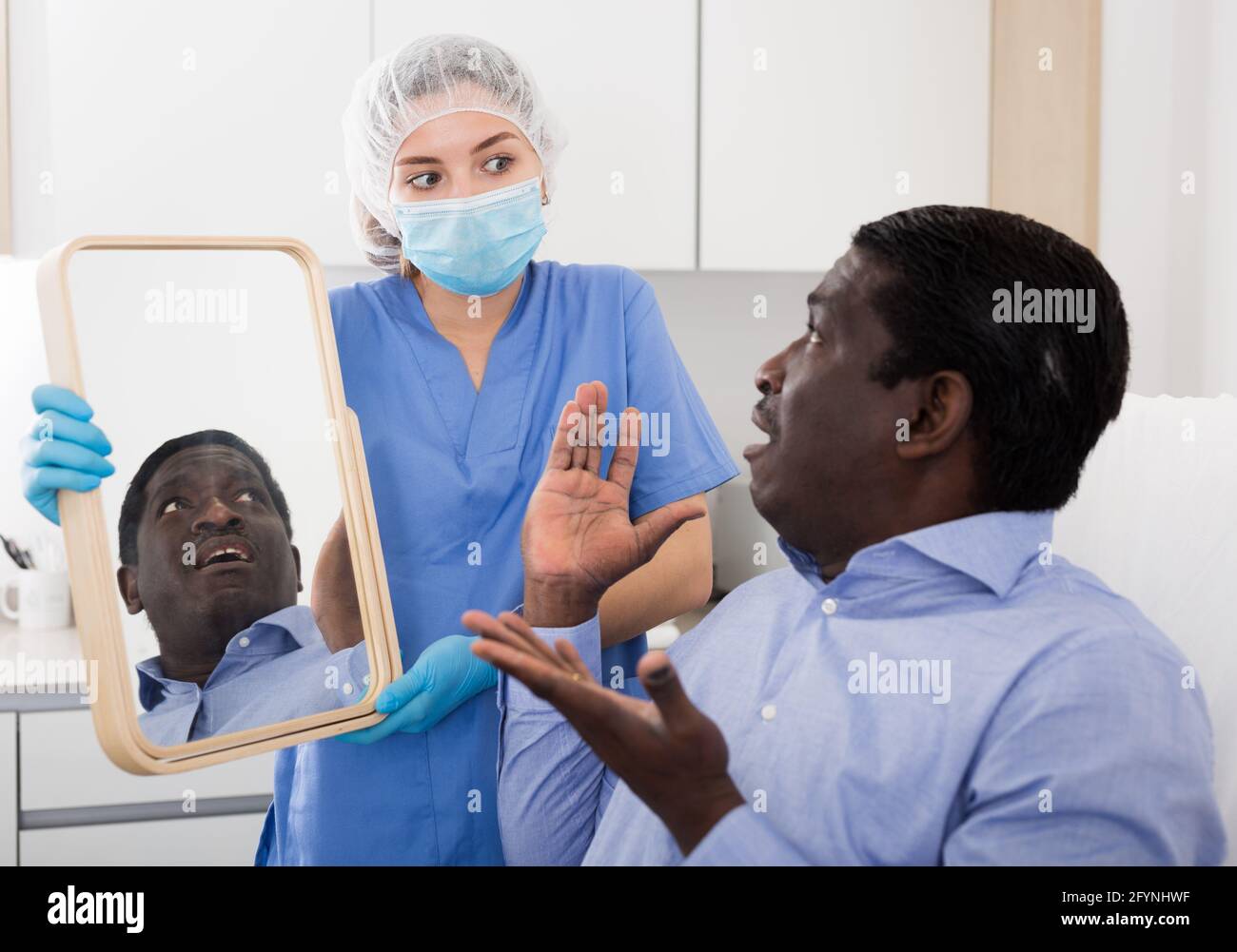 Indignant African American looking at mirror examining his face after ...