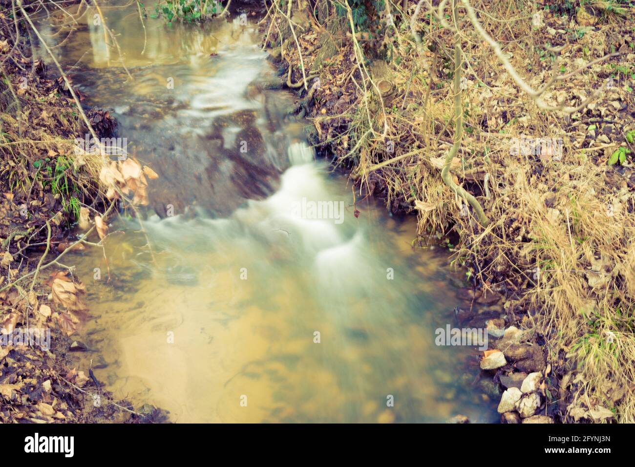High angle shot of a small thermal water stream and dried grass around ...