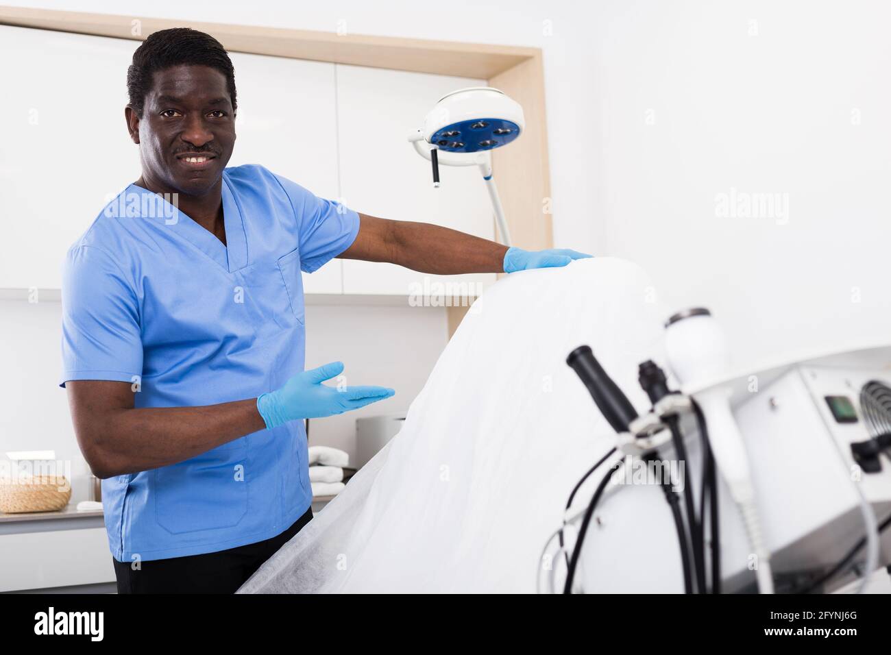Smiling professional African American male cosmetologist inviting ...