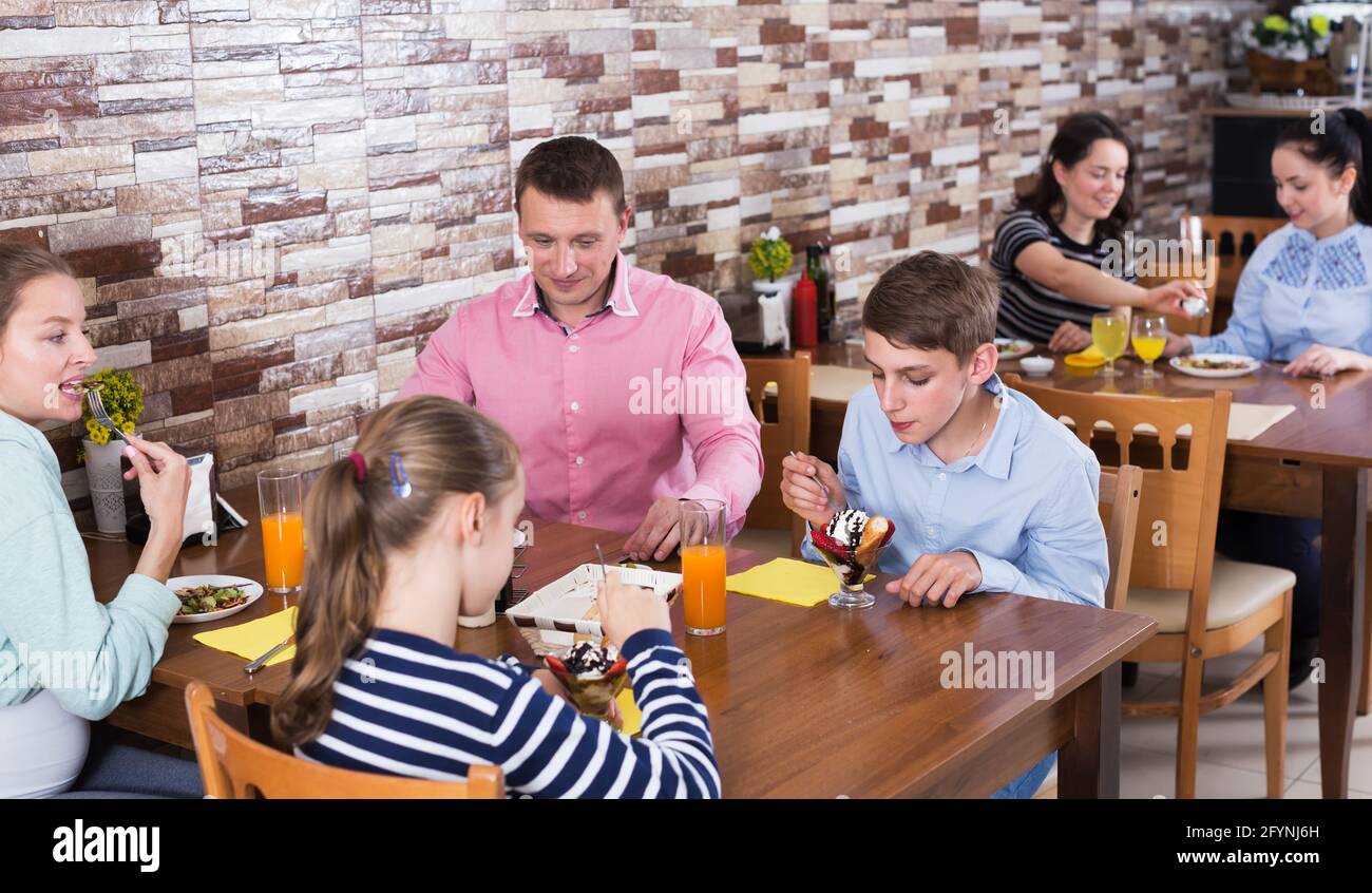 Happy parents with children dining together in modern family cafe Stock ...