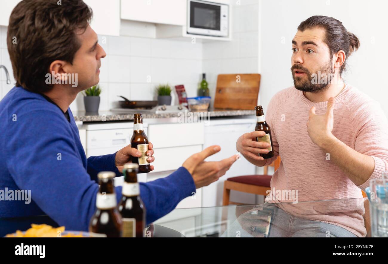 Drunk men sitting at table and drinking beer indoor Stock Photo - Alamy