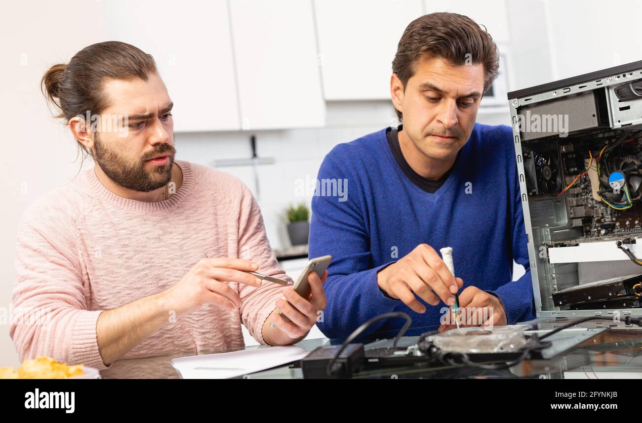 Two men repairing a desktop computer and drink beer Stock Photo - Alamy