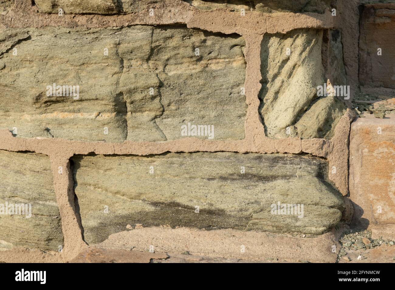 Background wall of green limestone and tan mortar, stone eaten away ...