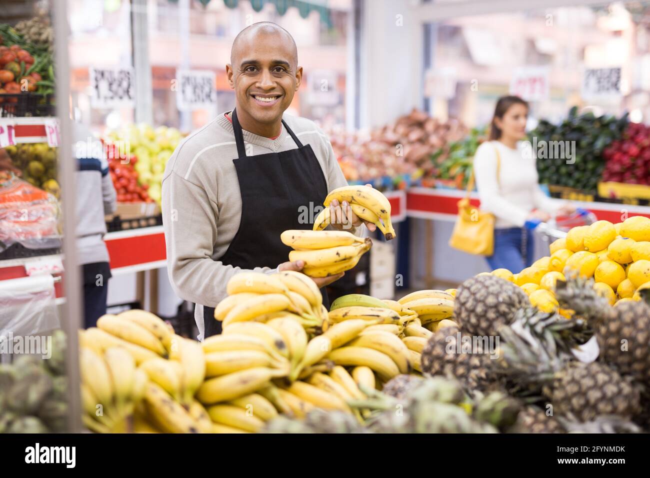 Portrait of latino-american worker in supermarket with bananas Stock ...