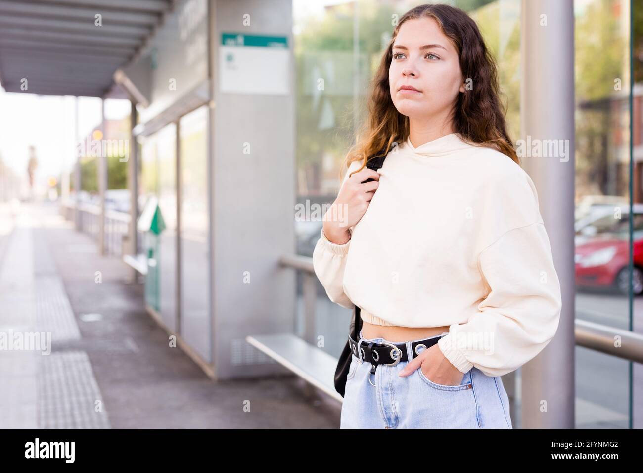 Beautiful young woman waiting for tram on platform of public transport ...