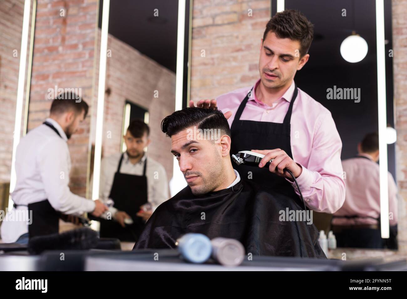 Professional hairdresser man doing styling of handsome guy with ...