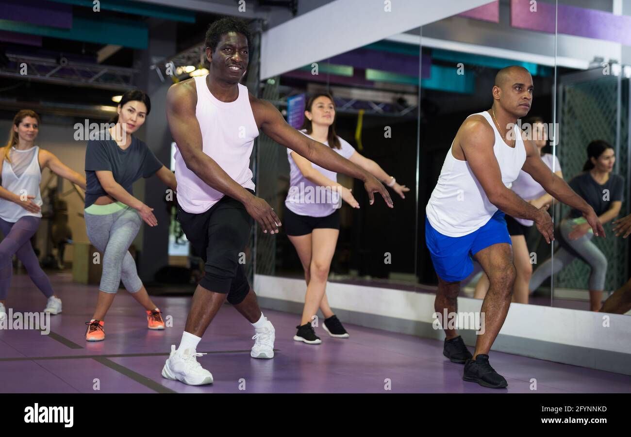Multiethnic group of adult people practicing active dancing in class at ...
