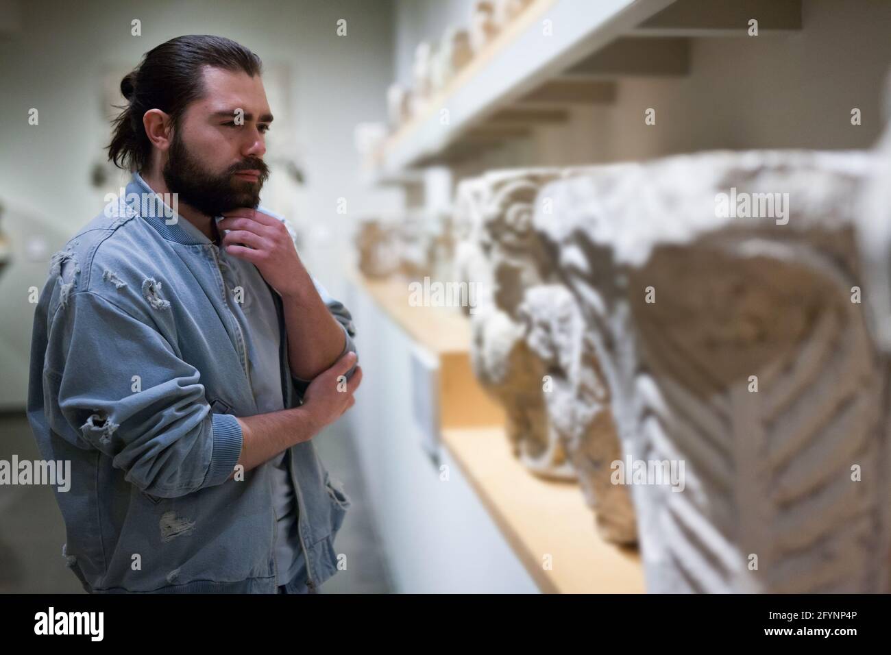 Man looking at stone architectural elements in historical museum hall ...