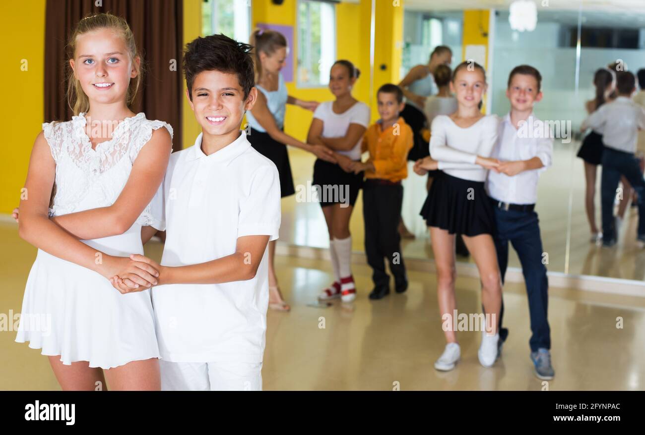 Happy children dancing in dance-hall with young female coach and ...