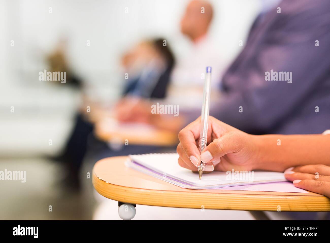Closeup of female hand taking notes in notepad during lecture in ...