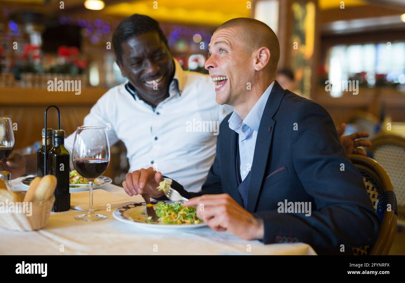 Two handsome men in classic suits having dinner together at restaurant ...