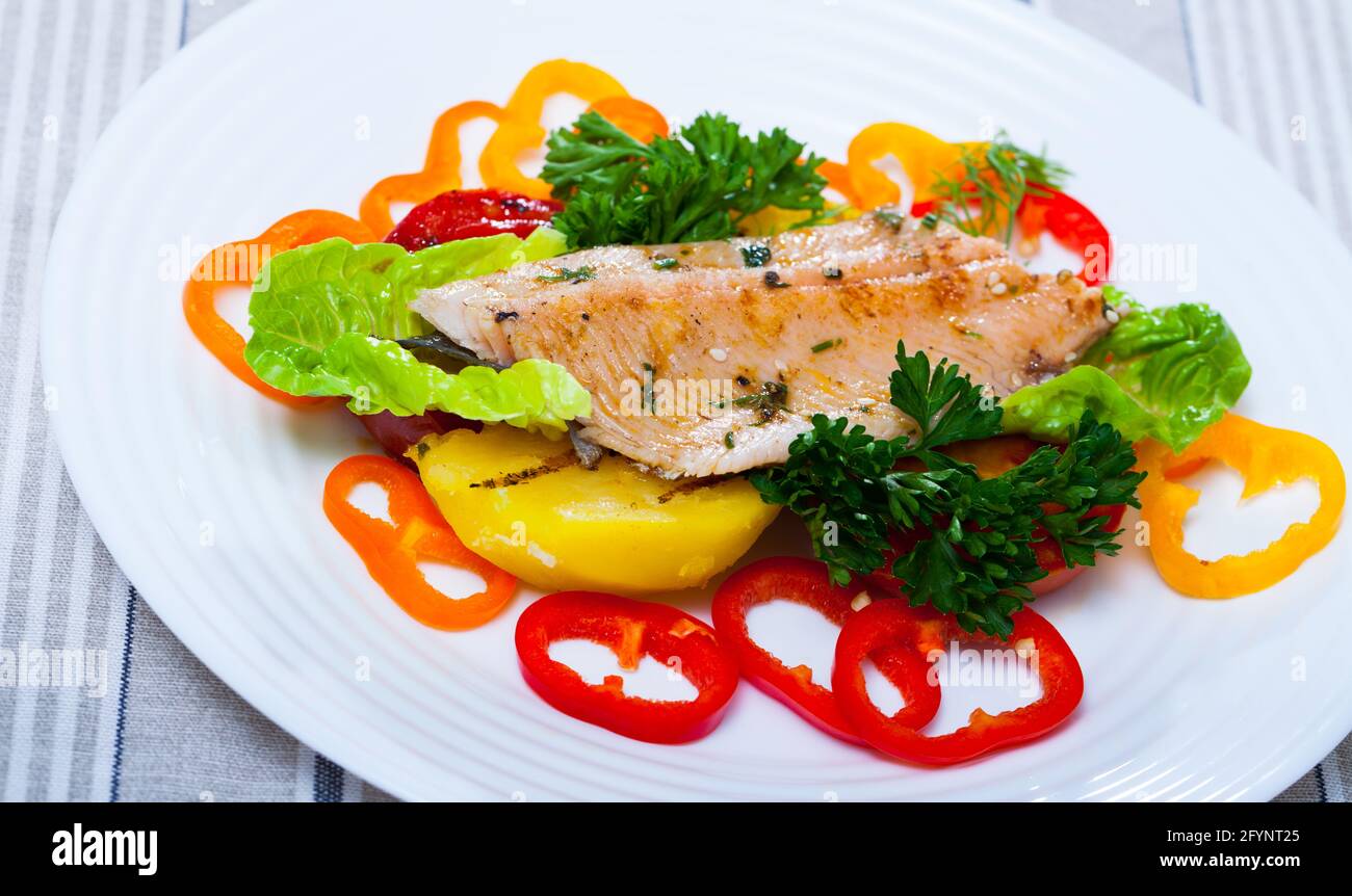 Delicious fried trout fillets served with baked potato, bell peppers ...