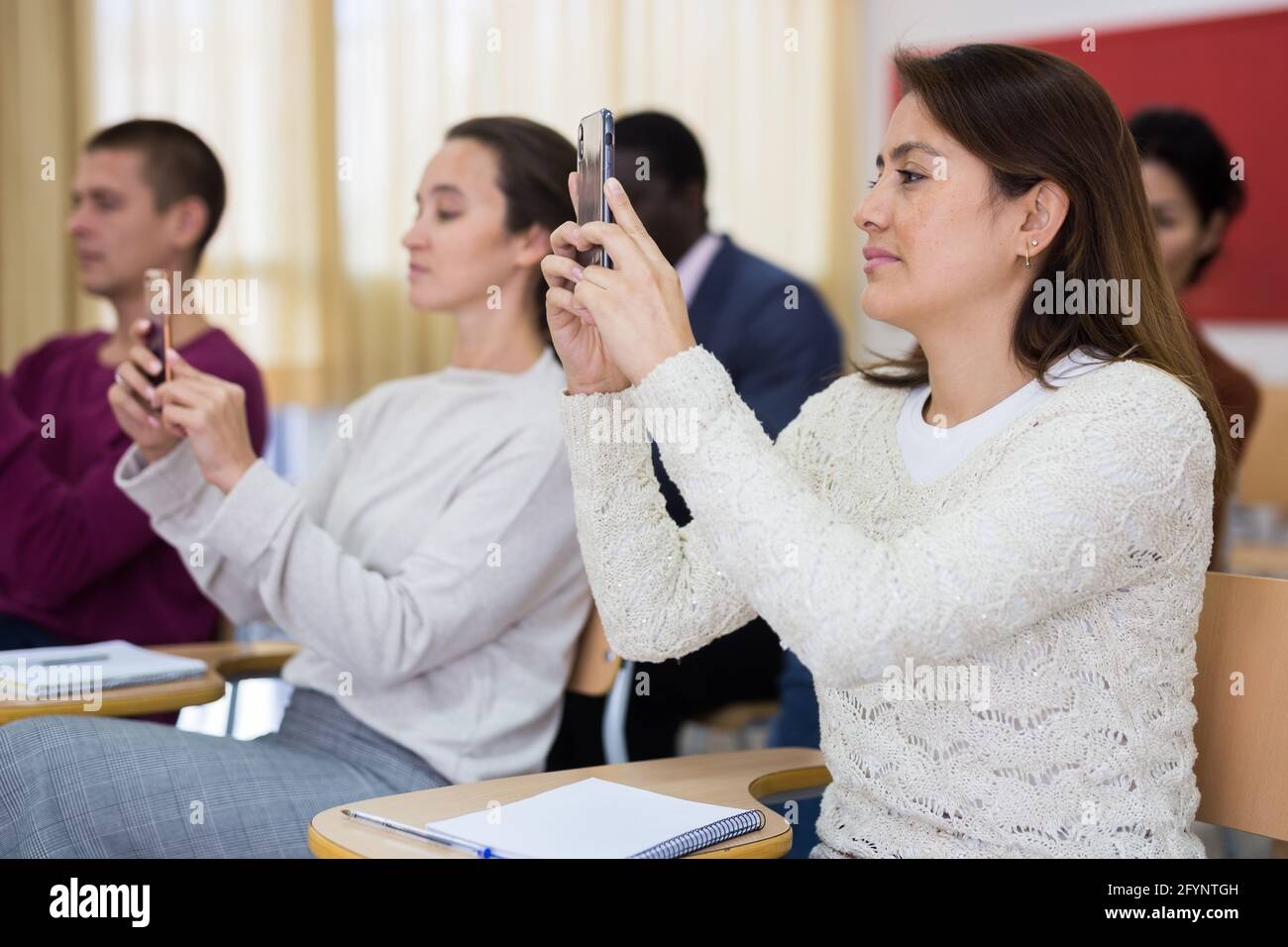Female student take pictures on the smartphone in classroom Stock Photo ...