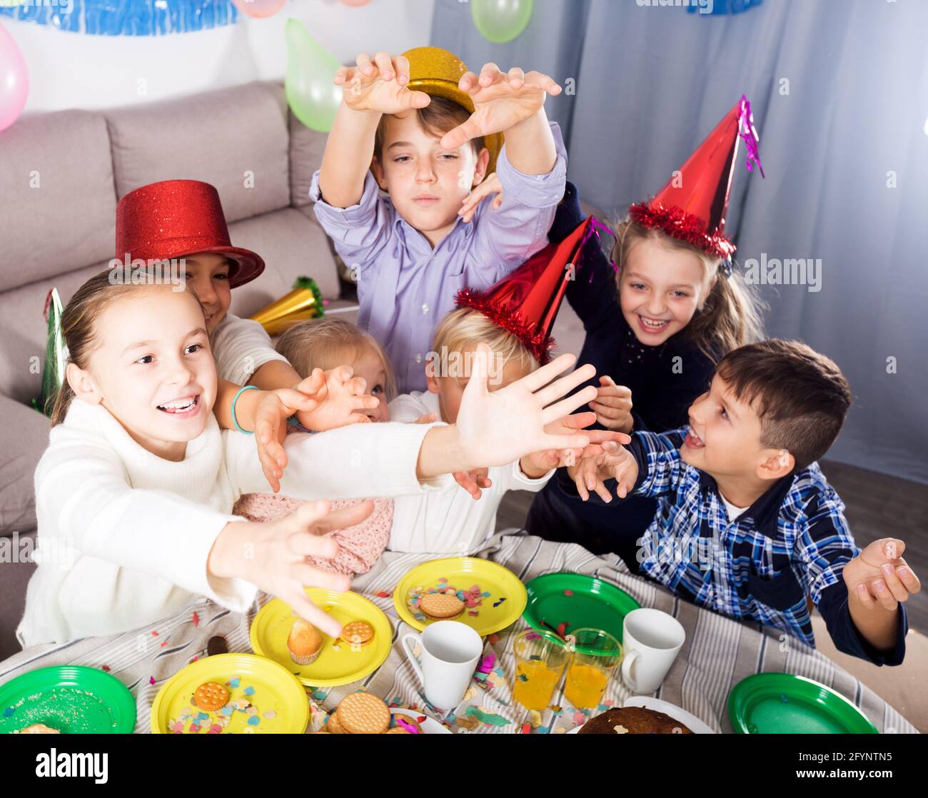 Glad group of children having fun during friend’s birthday party at his ...