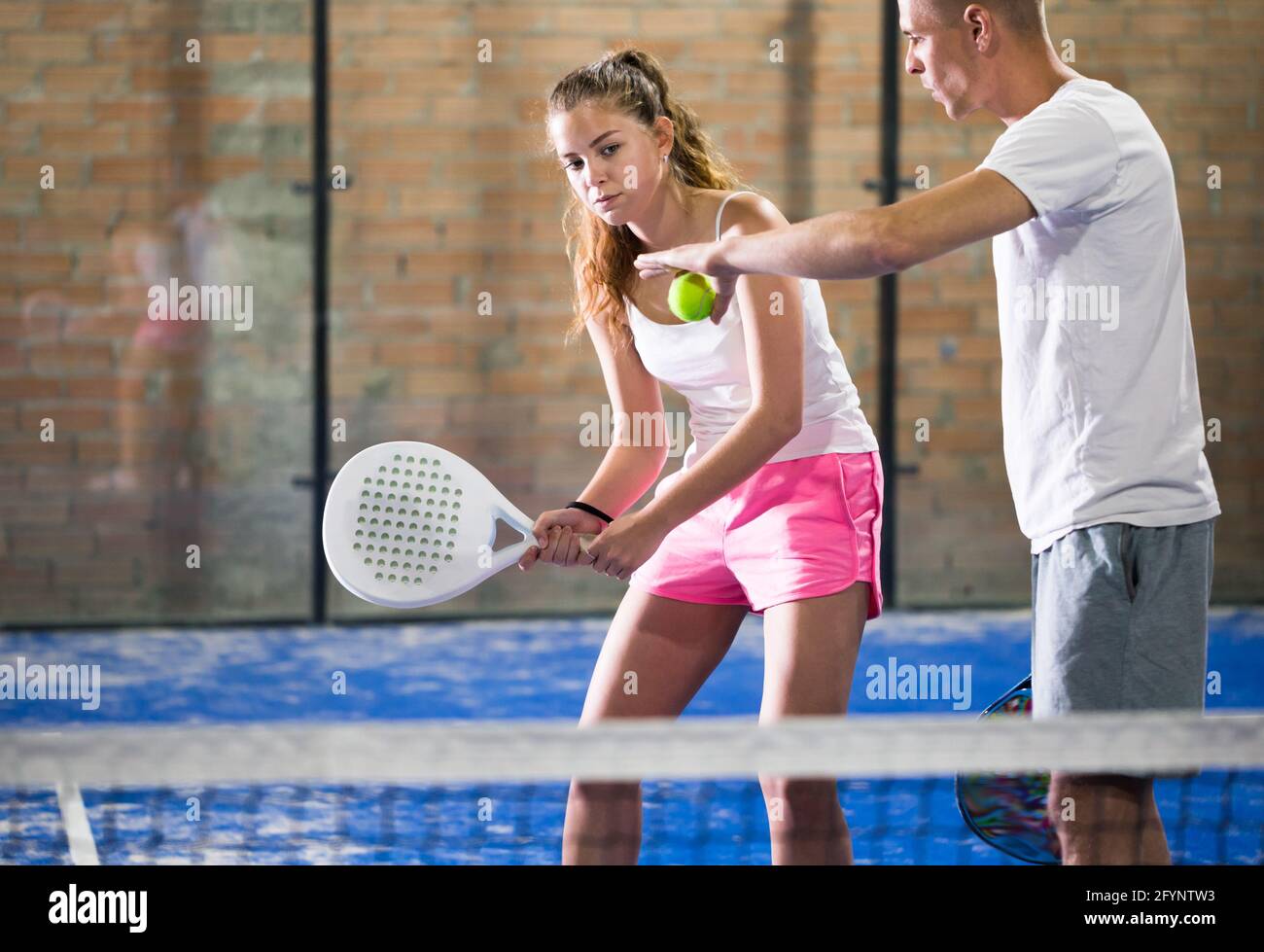 Trainer teaches a woman to play padel on tennis court Stock Photo - Alamy