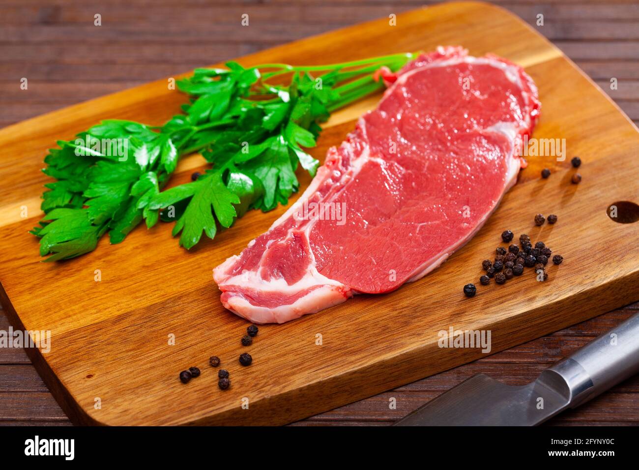 uncooked beef marbled steak served with pepper and parley on the table ...