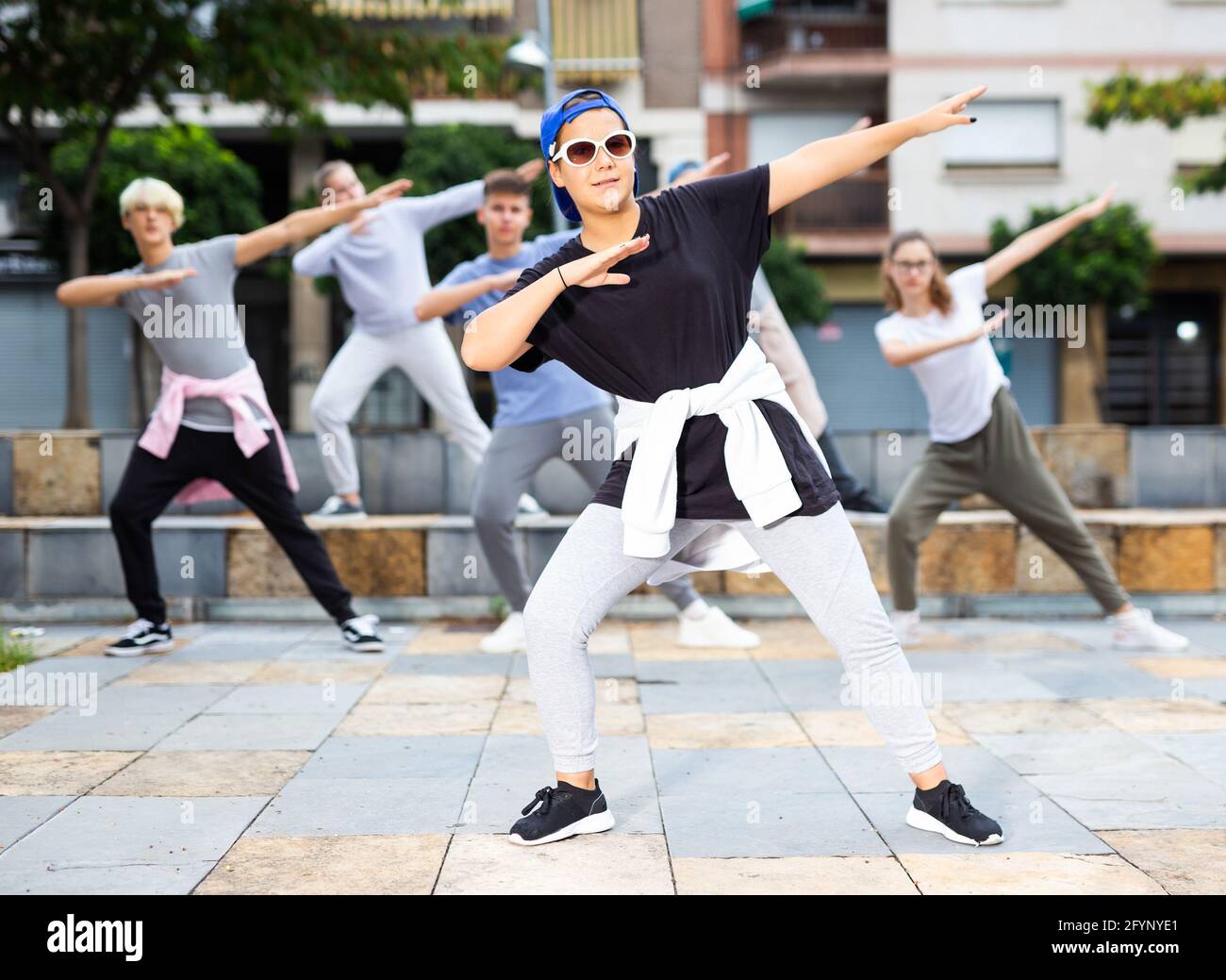Positive girl dancing modern choreography with group of teenagers on ...