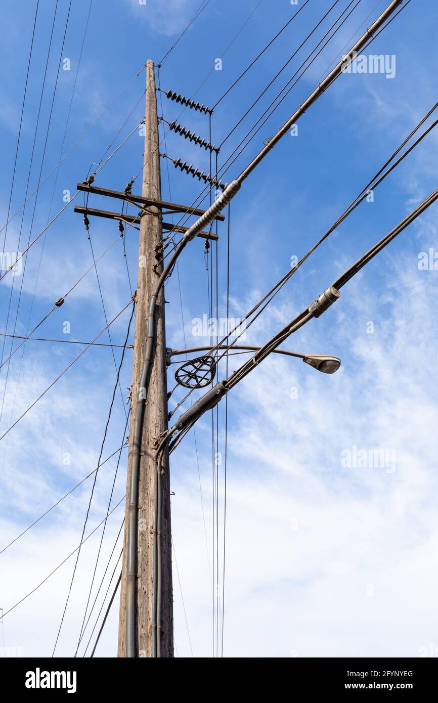 Huge single wood power pole carrying cables, fiber optics, and street ...